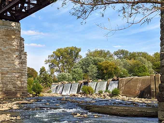 Framed by historic bridge remnants, this waterfall view combines industrial heritage with natural beauty in one stunning snapshot.