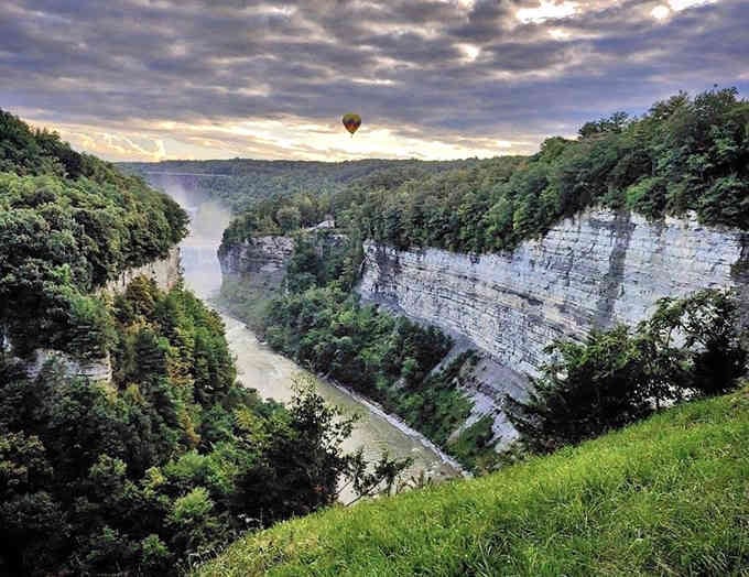 A hot air balloon drifts above the gorge at sunrise, adding a touch of whimsy to this already spectacular view.