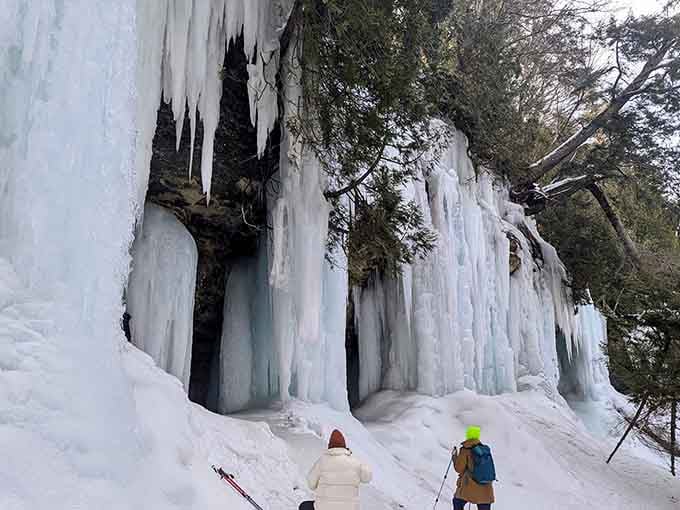 Towering ice walls dwarf winter hikers exploring this frozen cathedral, where Mother Nature shows off her architectural skills.