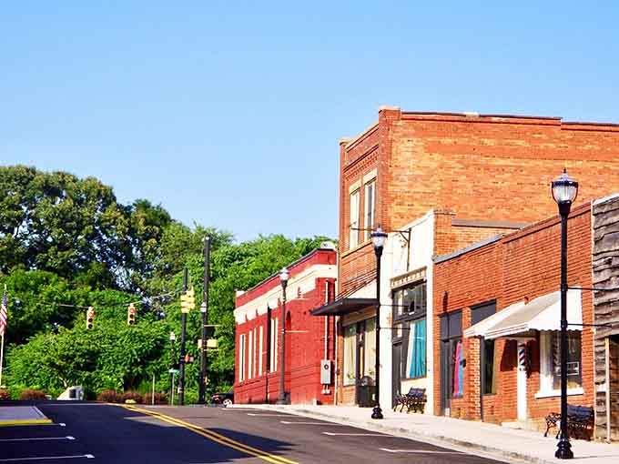 Lush green trees frame Inman's red brick buildings, creating shade and character that air-conditioned malls simply can't replicate.