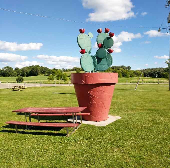 An oversized potted cactus towers over picnic tables, adding desert whimsy to prairie landscapes unexpectedly.