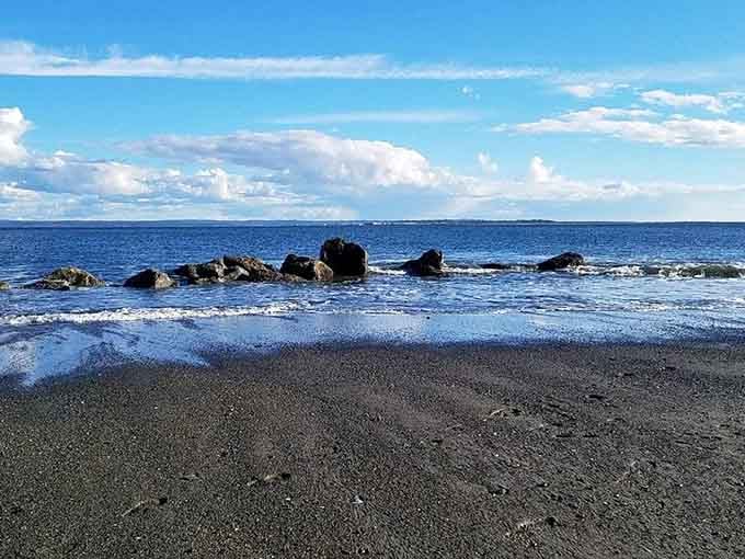 Smooth stones dot the shoreline like nature's own zen garden beneath dramatic clouds and brilliant blue water.