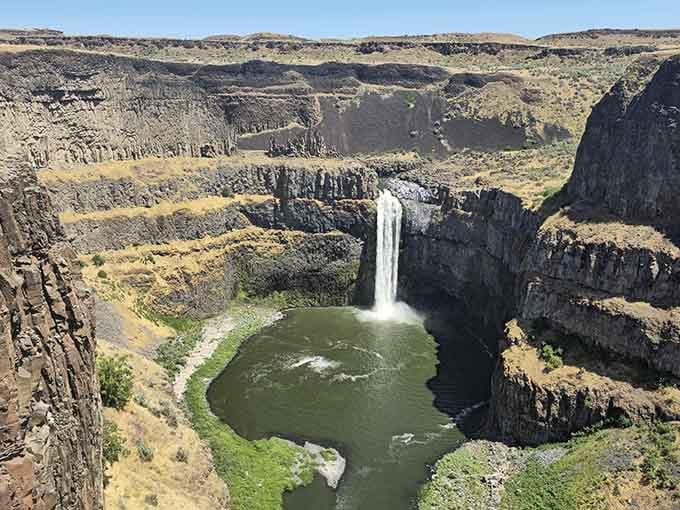Water plunges into a circular basin carved from dark basalt, nature's own amphitheater of raw power.