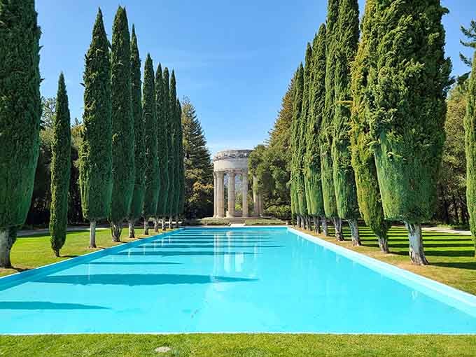 Towering cypress trees line this brilliant blue pool, creating a scene straight from an Italian villa's grandest dreams.