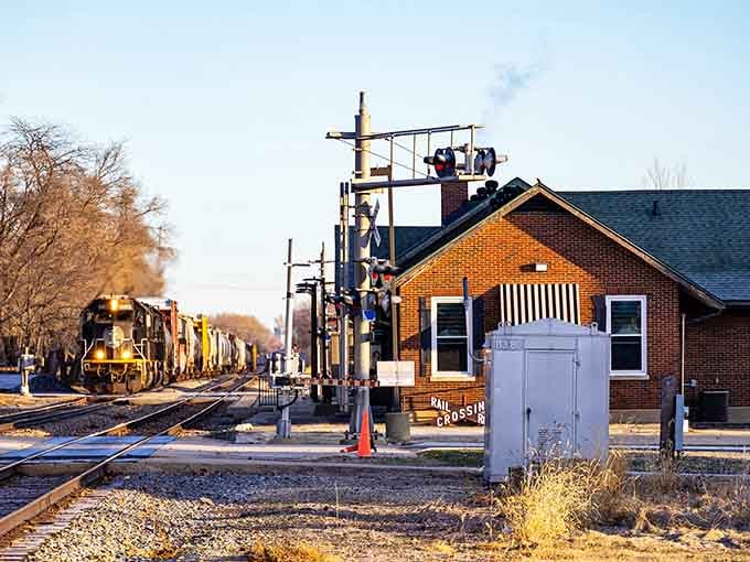 Railroad crossing signals stand ready while freight trains still rumble through&mdash;a reminder of the iron horses that built America.