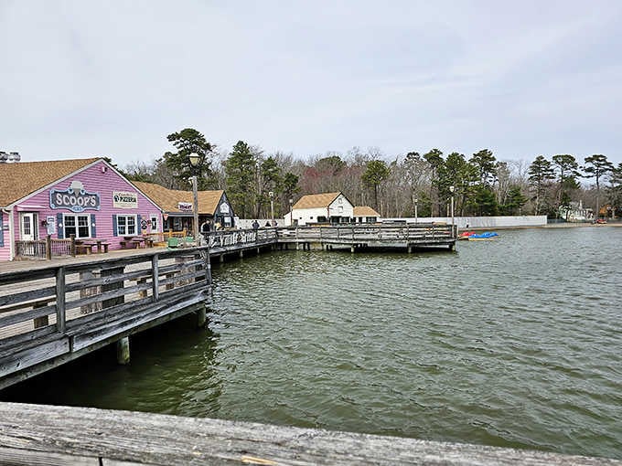 Cheerful pink buildings perch on wooden docks above tranquil waters, creating a storybook village scene that delights visitors.