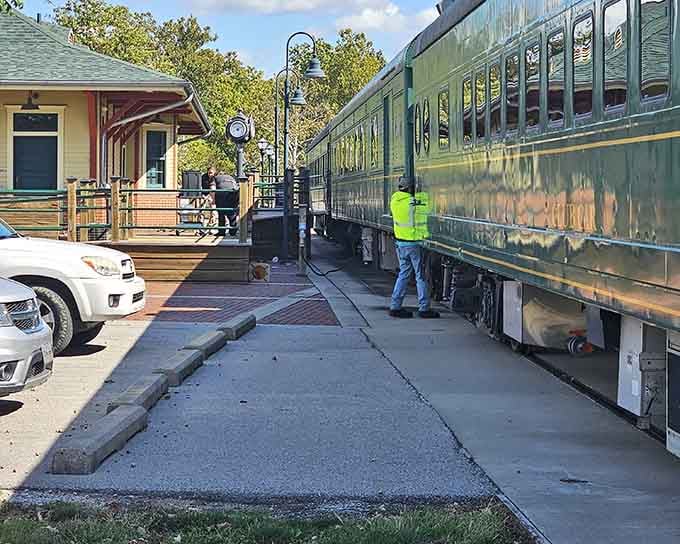 The vintage green passenger car sits beside a charming station, where ornate lampposts add old-fashioned elegance everywhere.