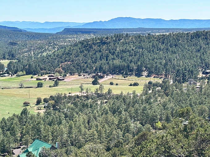 Rolling meadows dotted with pines stretch toward distant peaks, painting a landscape that belongs on a jigsaw puzzle.