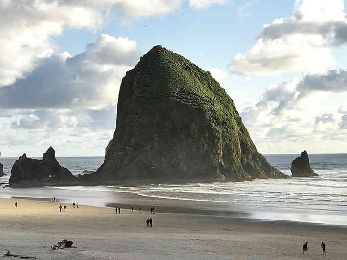 That massive sea stack makes humans look tiny, reminding us nature always steals the show here.