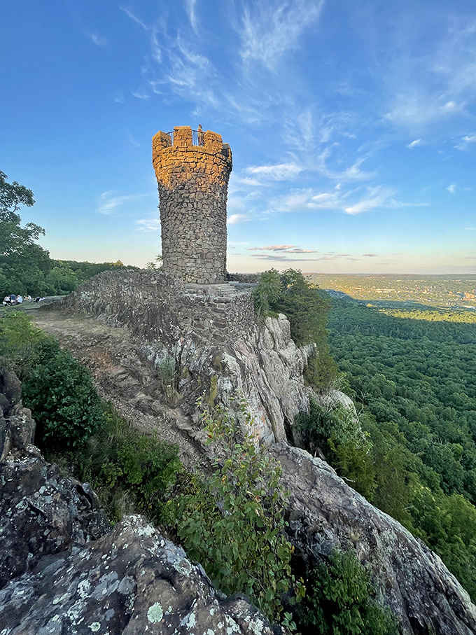 Sunset gilds the ancient stonework as the tower rises dramatically from its natural rock foundation.