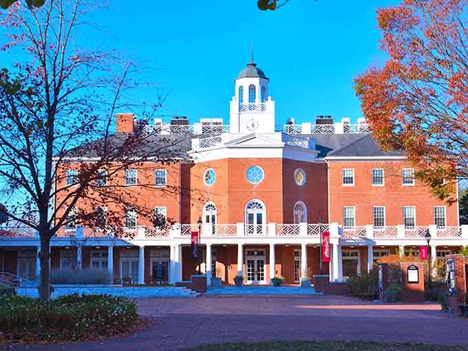 That brick colonial building stands proud in autumn splendor, framed by trees showing off their best fall colors.