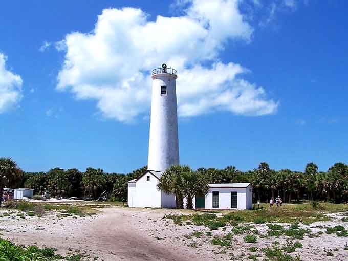 The pristine tower stands against blue sky like a exclamation point, announcing its presence with quiet confidence and sandy surroundings.