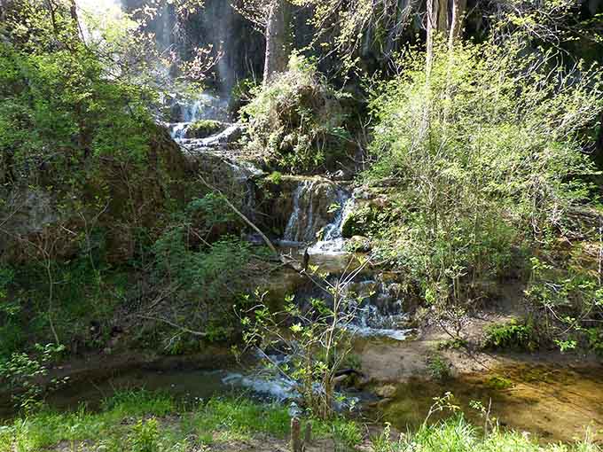 Multiple tiers of waterfalls flow through dense forest, each level more enchanting than the last like nature's own fountain display.