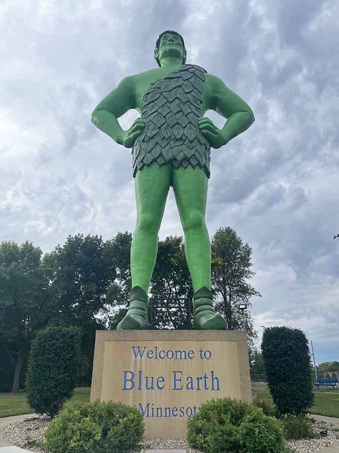 Manicured shrubs frame the welcome sign perfectly, proving even giants appreciate good landscaping and warm hospitality.