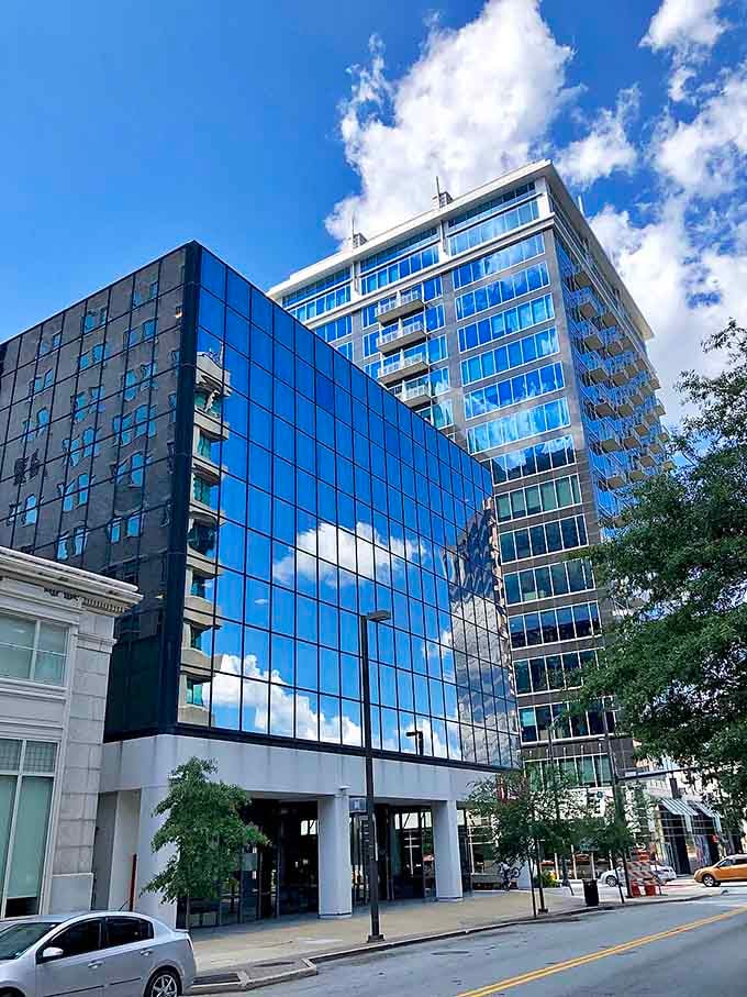 Modern glass and steel reach skyward, reflecting clouds so perfectly you might think the building is made of sky itself.