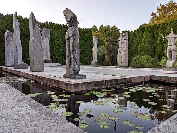 These towering stone figures rising from lily pads create a scene that's part ancient temple, part contemporary dreamscape.