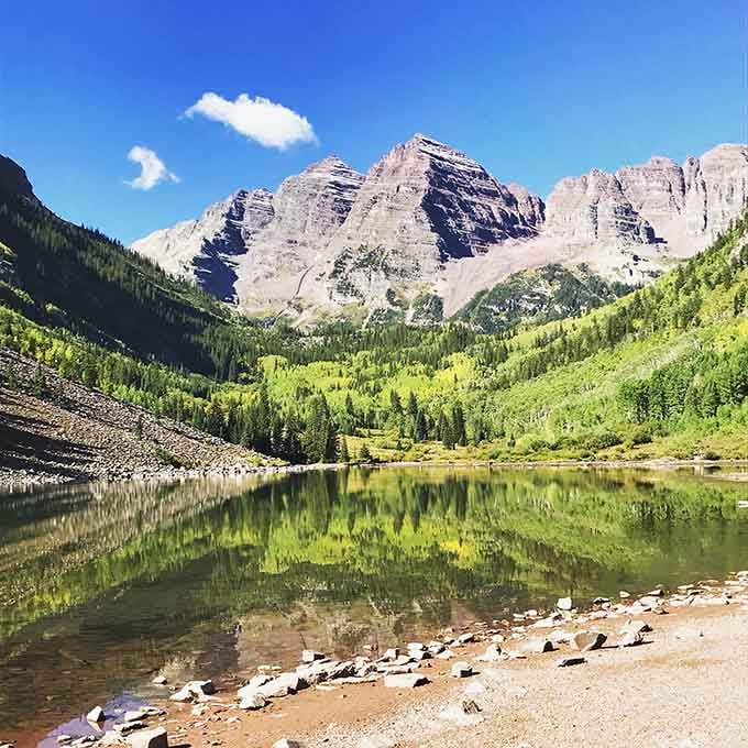 Bright aspens frame the maroon mountains in their full glory, reflecting like a doubled masterpiece below.