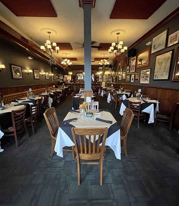 Classic steakhouse elegance radiates from every corner of this dining room where white tablecloths meet warm wooden accents beautifully.