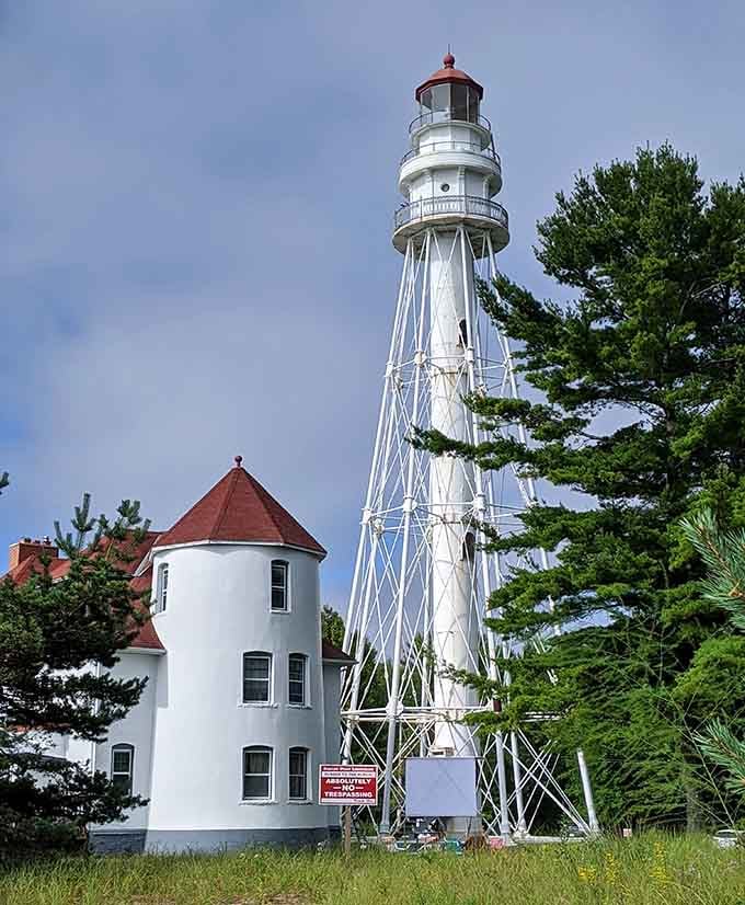 The metal tower's intricate lattice design catches sunlight like a giant piece of architectural jewelry against the evergreen backdrop.