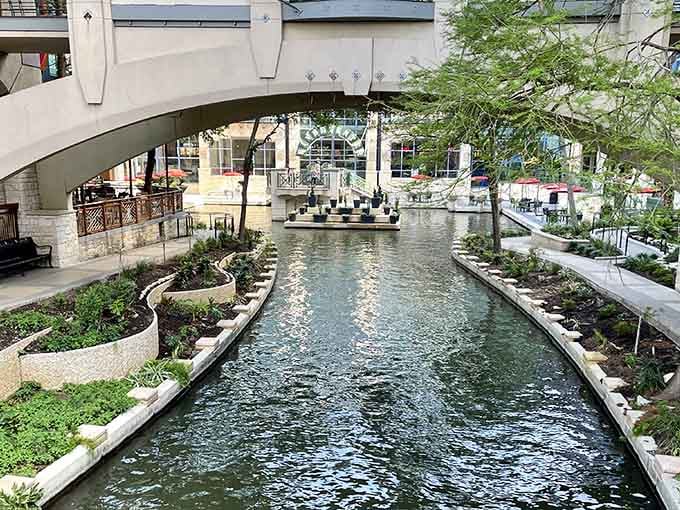 Graceful bridges arch over calm waters, connecting pathways where locals and visitors stroll beneath a canopy of green.
