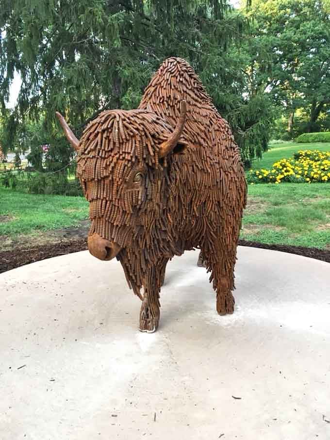 Textured organic forms crafted from natural materials create a shaggy creature that seems almost alive in dappled shade.