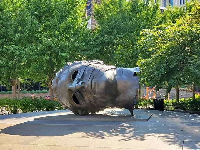 This oversized metallic head rests peacefully in the park, inviting visitors to ponder what dreams giants might have.