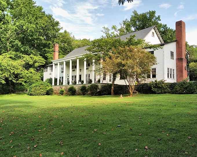 Tall white columns and sprawling green lawns evoke Southern plantation elegance with a touch of Greek Revival grace.