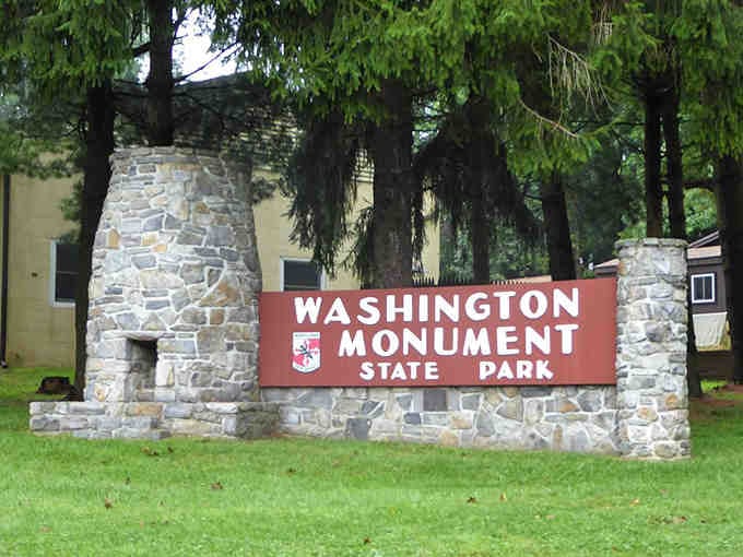 The first monument to Washington stands proudly behind this welcoming sign, inviting you to discover America's beginnings.