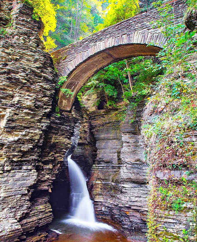 That stone bridge arching over the waterfall proves nature and human craftsmanship can create magic together.
