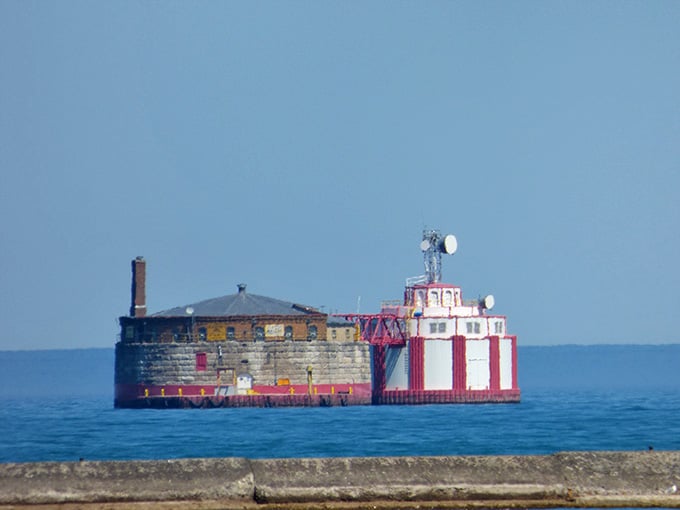 The weathered brick structure sits stoically in the lake, its candy-striped lighthouse attachment keeping watch over passing boats.