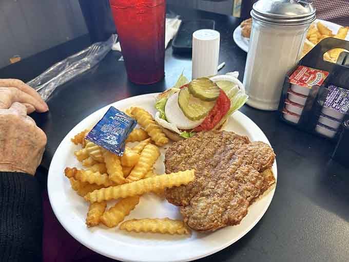 A satisfying meal with crispy fries, a savory patty, and fresh toppings, all on one plate.