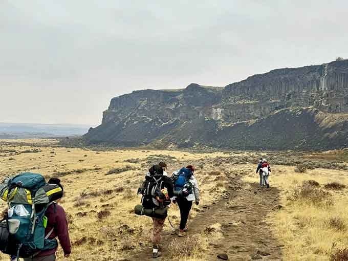 Following fellow adventurers toward those cliffs, backpacks loaded with hope, snacks, and probably too many water bottles.
