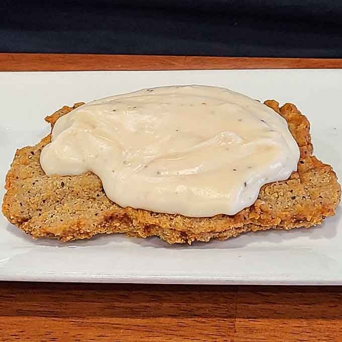 Country fried steak blanketed in white gravy so generously applied it's practically a culinary duvet for your taste buds.