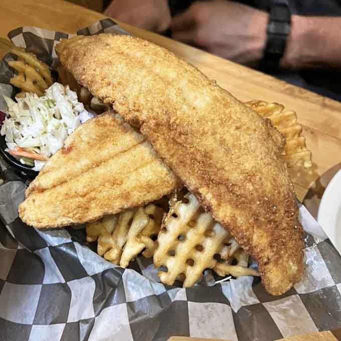 Golden fried fish and waffle fries served in a basket, comfort food elevated to an art form worth celebrating.