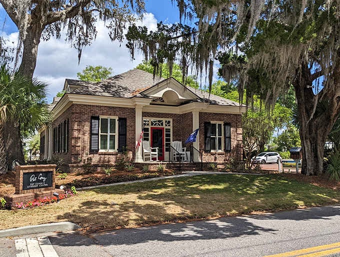 Moss-draped oaks frame this brick beauty like nature's own picture frame, absolutely nailing the Southern Gothic aesthetic.