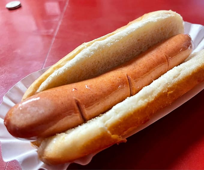 The steamed bun cradles that perfectly cooked dog like a warm, pillowy hug you can actually eat and enjoy.