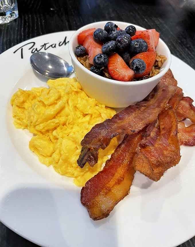 Scrambled eggs, crispy bacon, and fresh berries create a breakfast trinity that would make any morning person weep with joy.