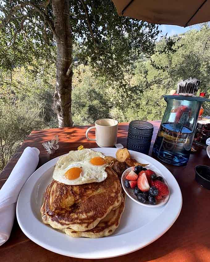 Stack of pancakes with fresh berries and two sunny eggs, because sometimes you need both sweet and savory to start right.