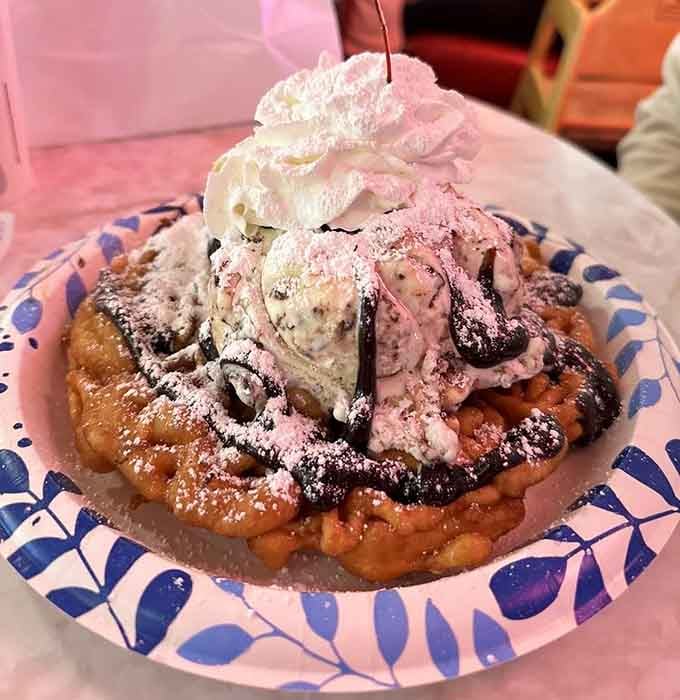 Funnel cake topped with ice cream, whipped cream, and chocolate drizzle, because subtlety was never the fifties' strong suit.