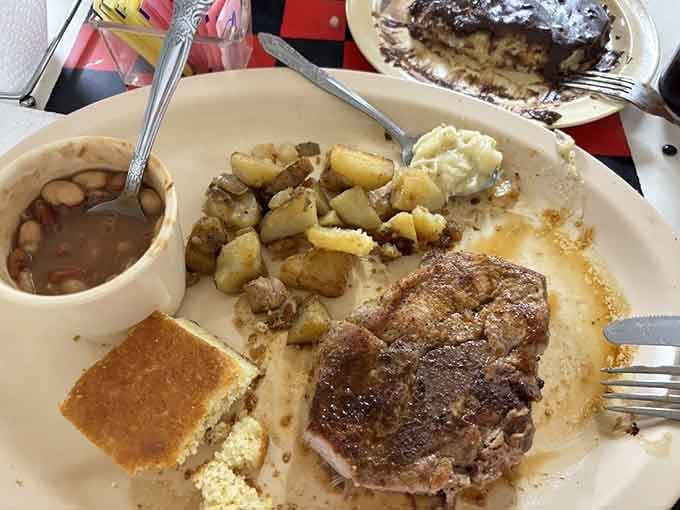 A thick, juicy pork chop alongside home fries and cornbread shows why people drive from counties away for this meal.