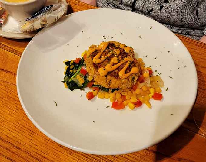 Perfectly golden crab cakes sitting pretty on a bed of vegetables, because presentation matters even when you're about to devour them.