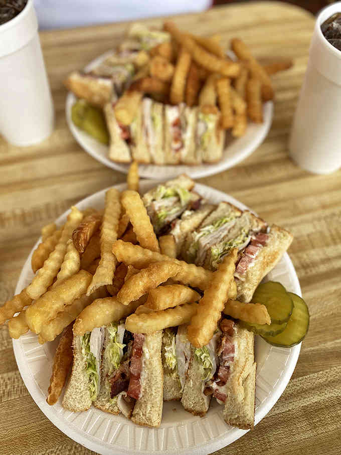 The club sandwich arrives stacked high with crispy fries, proving good things come in triple-decker packages.