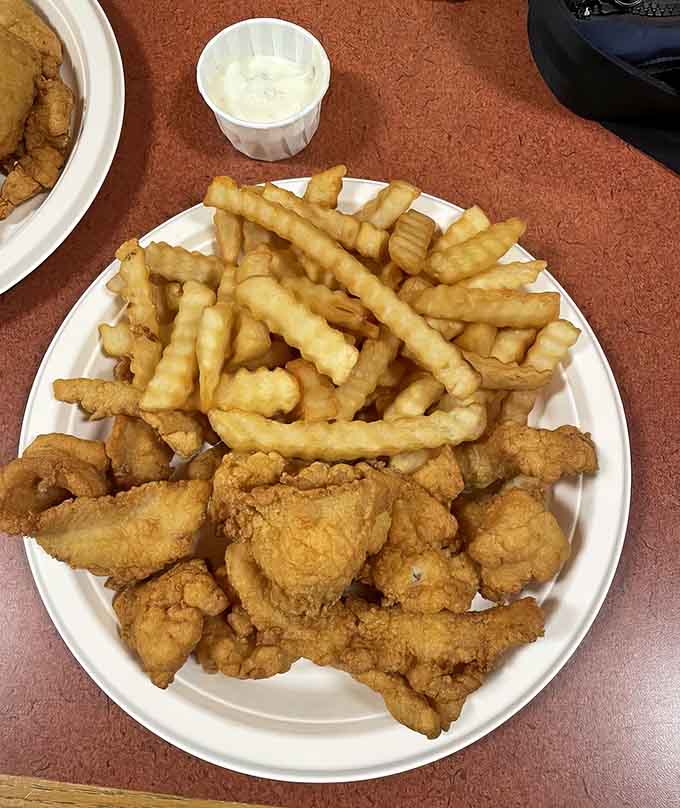 Golden fried seafood and crispy fries arranged like edible treasure on a simple white plate.