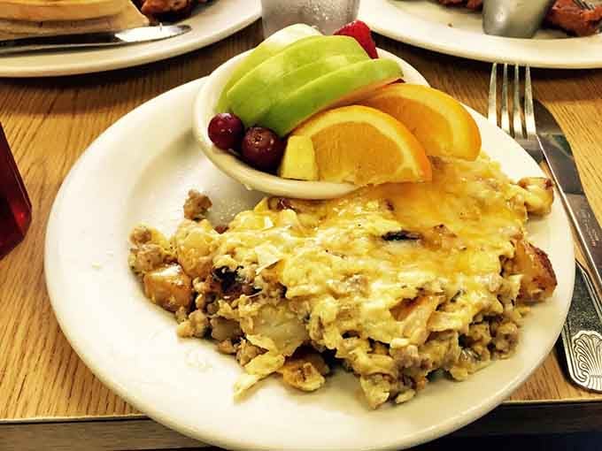 Scrambled eggs with sausage and fresh fruit, proving that balanced meals can still be indulgent when someone knows what they're doing.