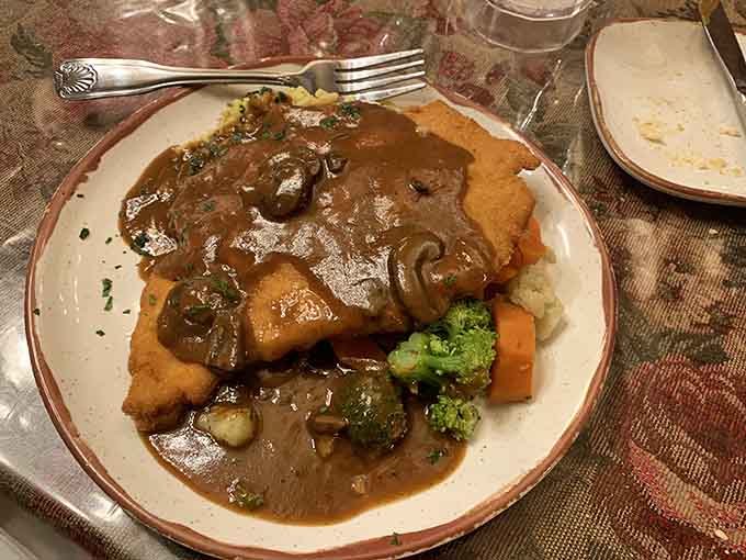 Golden schnitzel draped in mushroom sauce, making you question why you ever ordered anything else at any restaurant ever.