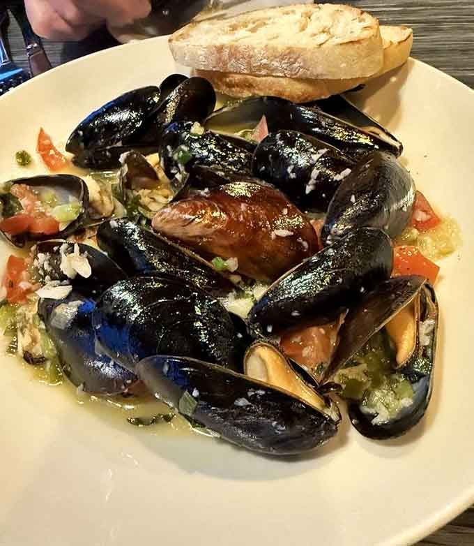 Fresh mussels swimming in garlic broth with crusty bread, the kind of dish that makes you forget your table manners.