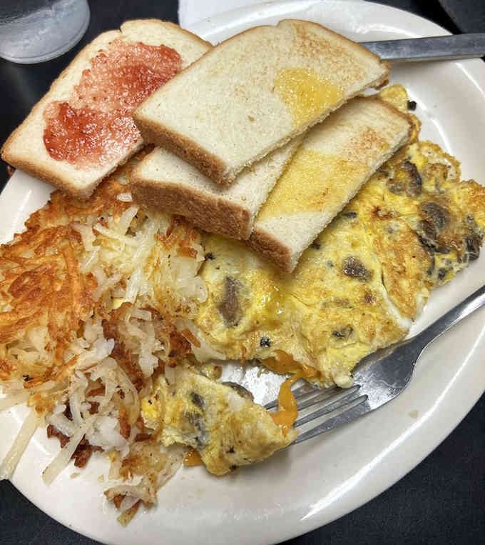 This mushroom omelette arrives fluffy and generous, accompanied by hash browns that deserve their own standing ovation.