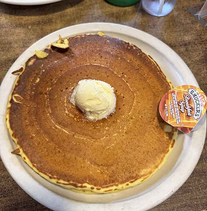 This pancake could double as a dinner plate, topped with butter that's already surrendering to the fluffy, golden warmth beneath.