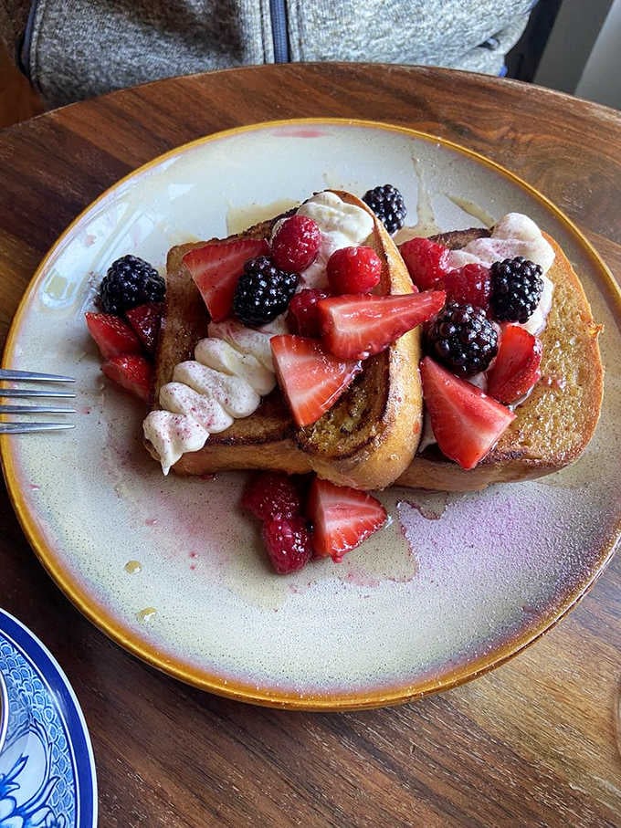 French toast piled high with berries and cream, because sometimes breakfast should feel like a celebration of life.