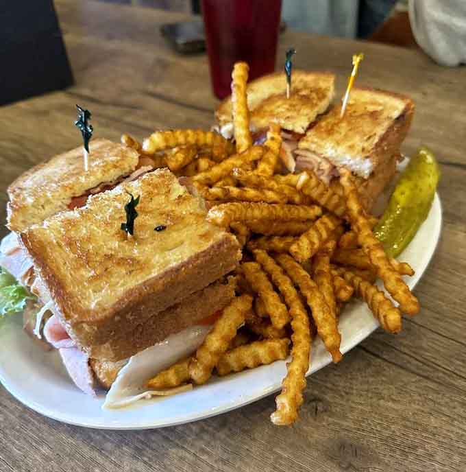 The Monster Club sandwich towers over its fries like a delicious skyscraper, daring you to take the first bite.